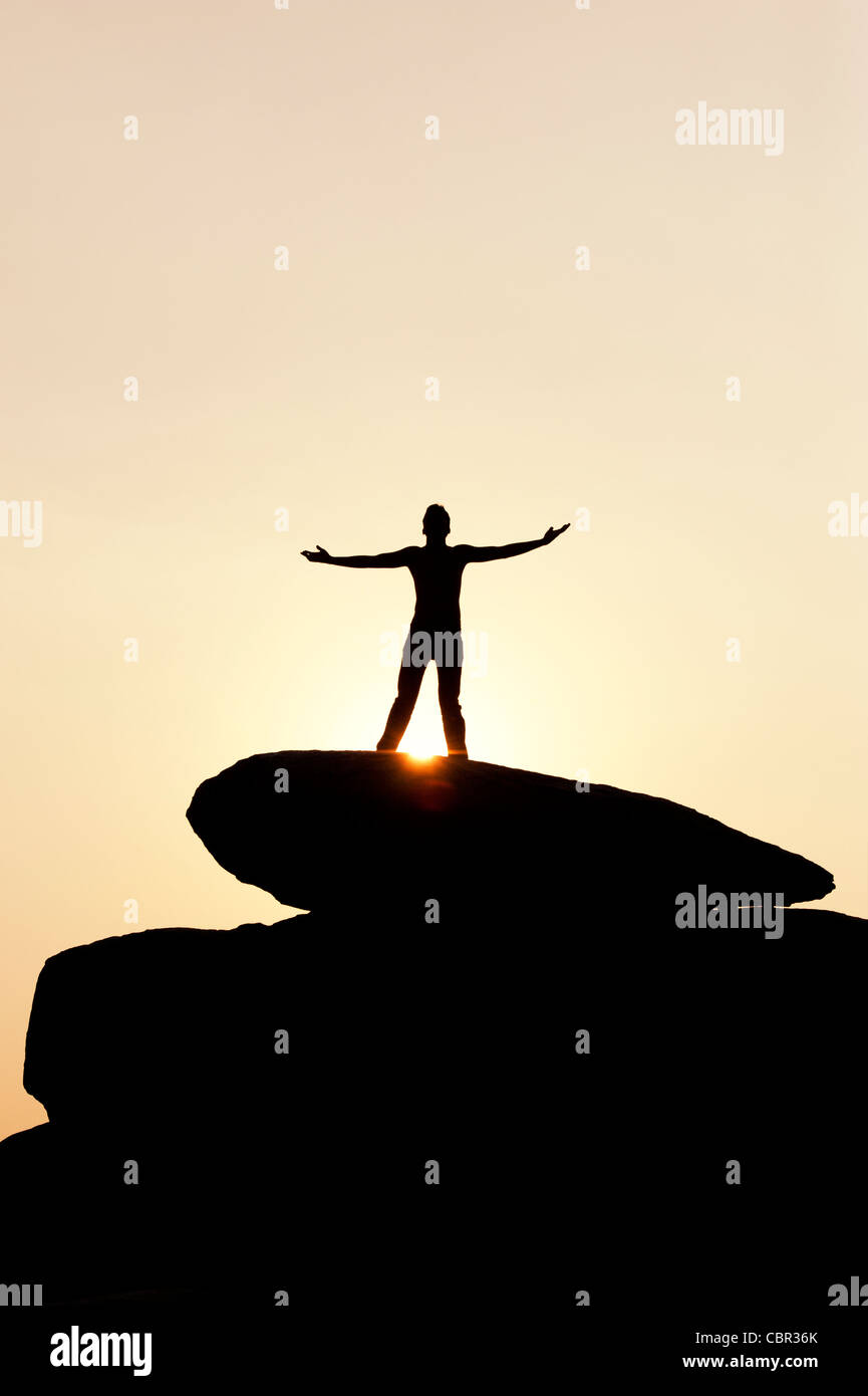 Indian man standing on a rock embracing the sun. Silhouette. India ...