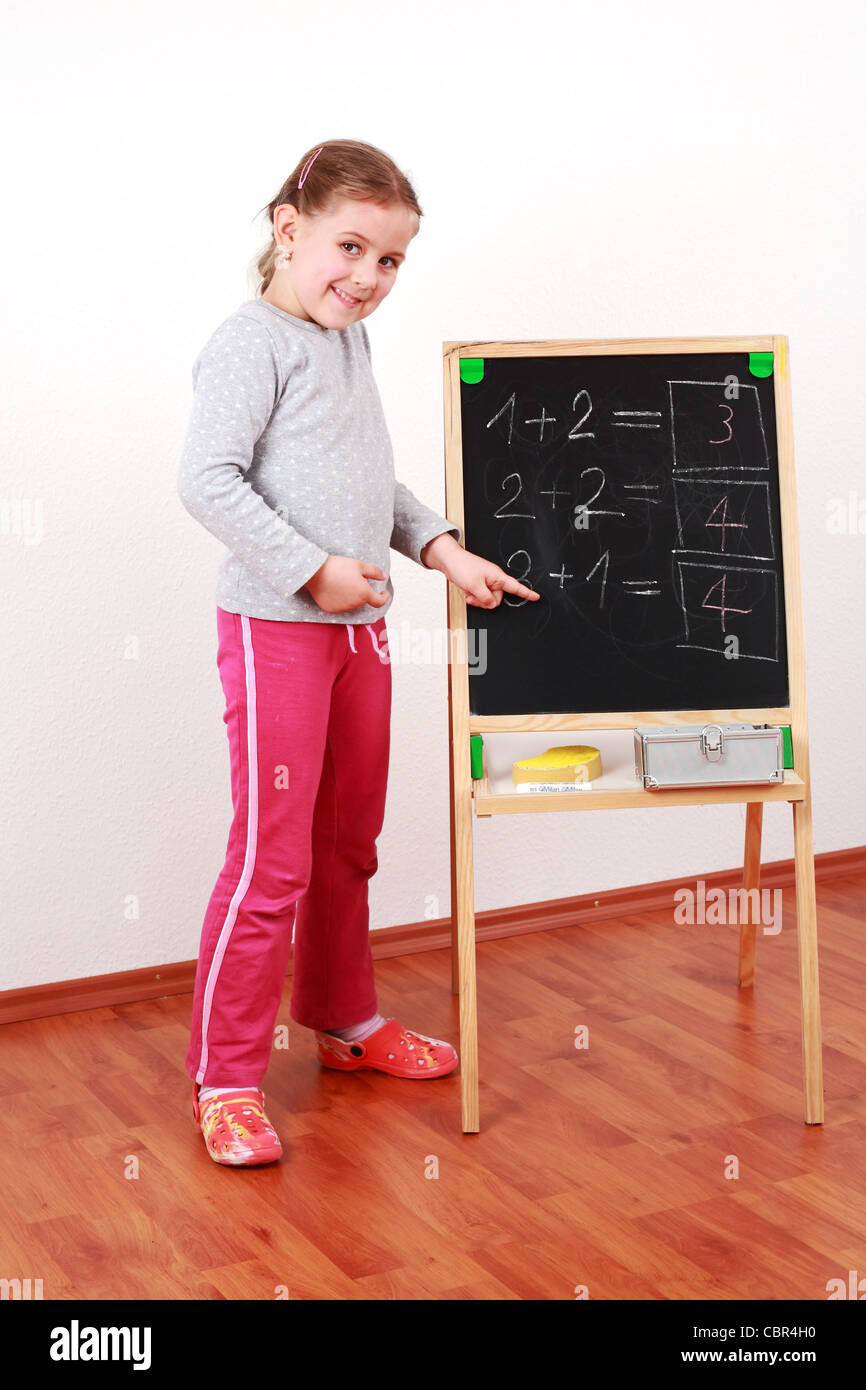 Cute girl doing the math on chalkborard Stock Photo - Alamy