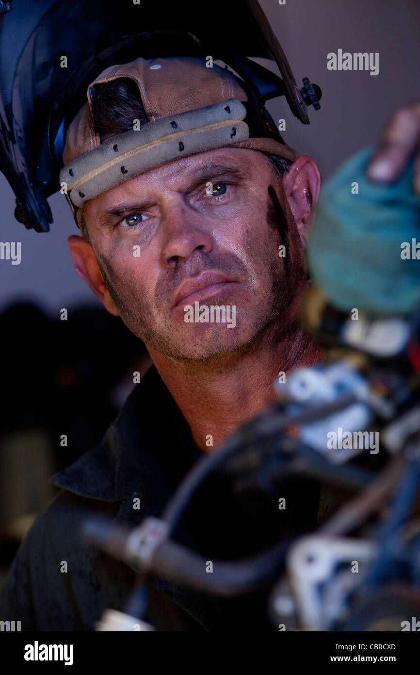 A grease covered blue collar working man takes a break, looking ...