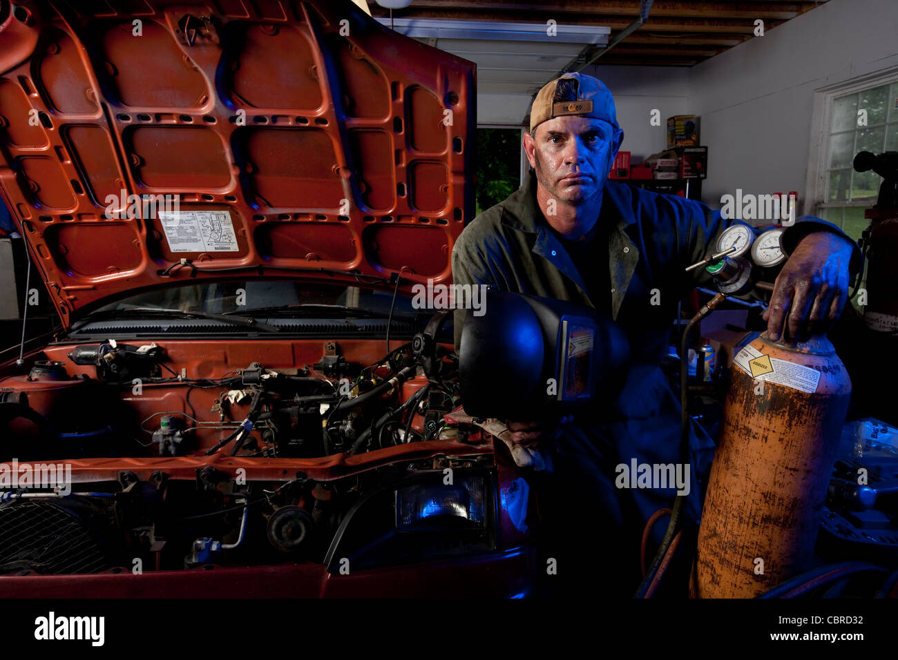 A grease covered blue collar working man takes a break, looking ...