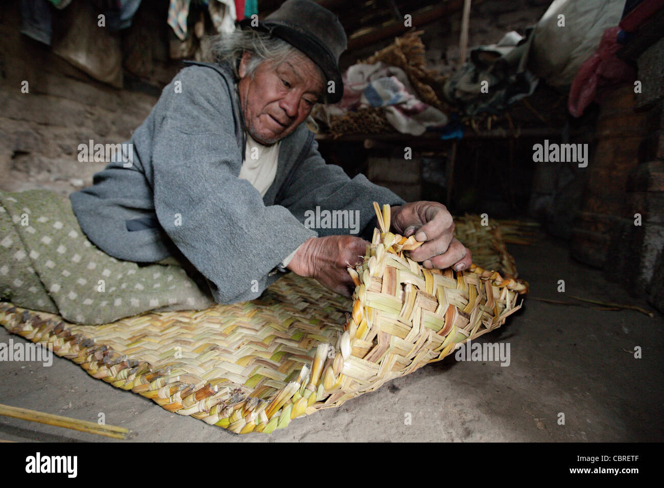 Man weaving a traditional straw carpet in a village near Otavalo ...