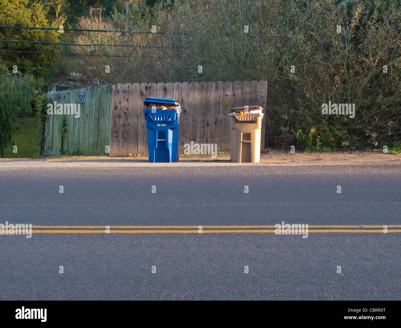 Two containers, one for recycle and the other for trash sit by the ...
