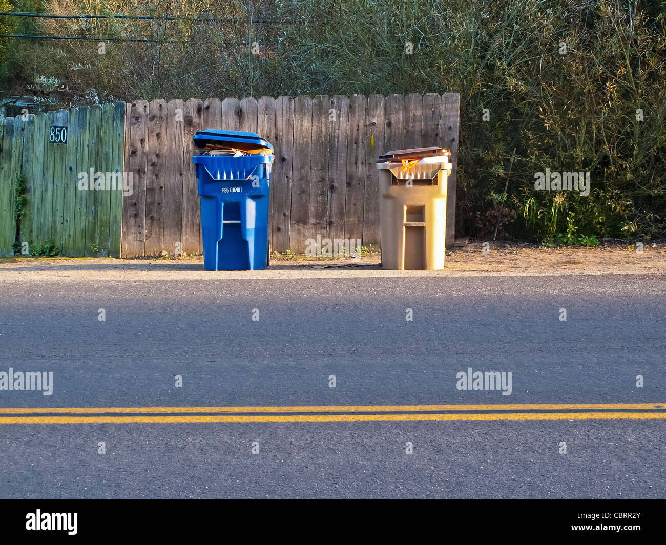 Two containers, one for recycle and the other for trash sit by the ...