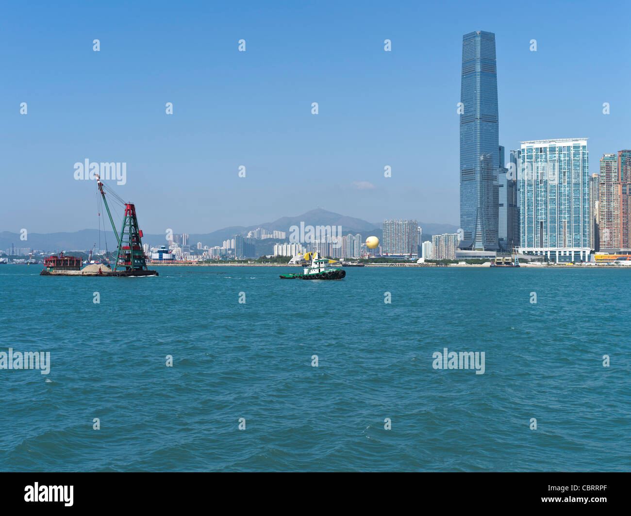 dh WEST KOWLOON HONG KONG Tug towing crane barge reclaiming harbour ...