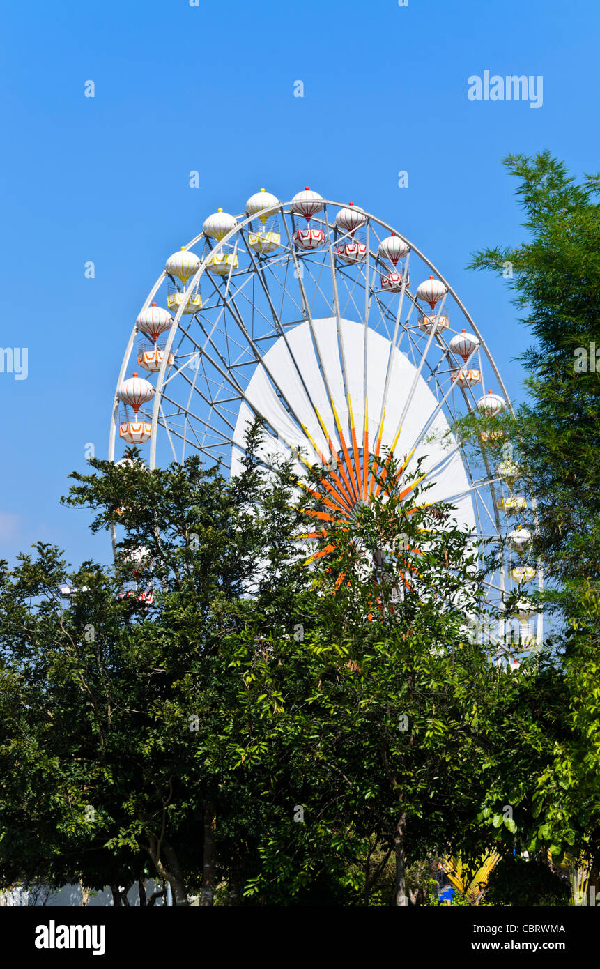 Huge Ferris wheel in clear blue sky behind trees at Royal Flora ...