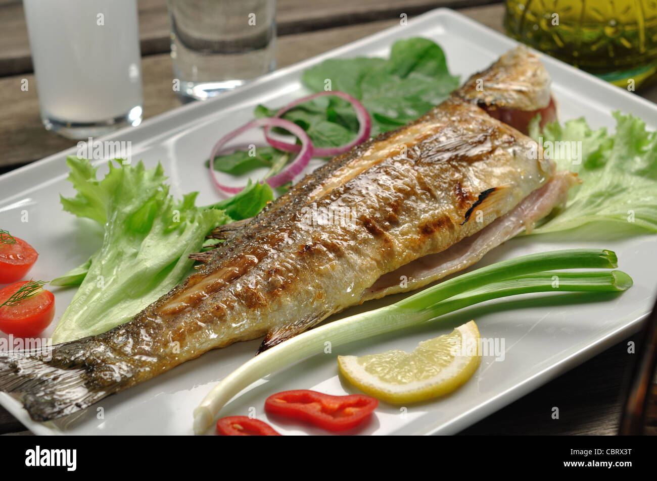 char grilled sea bass fish served with garnish and traditional Greek ...