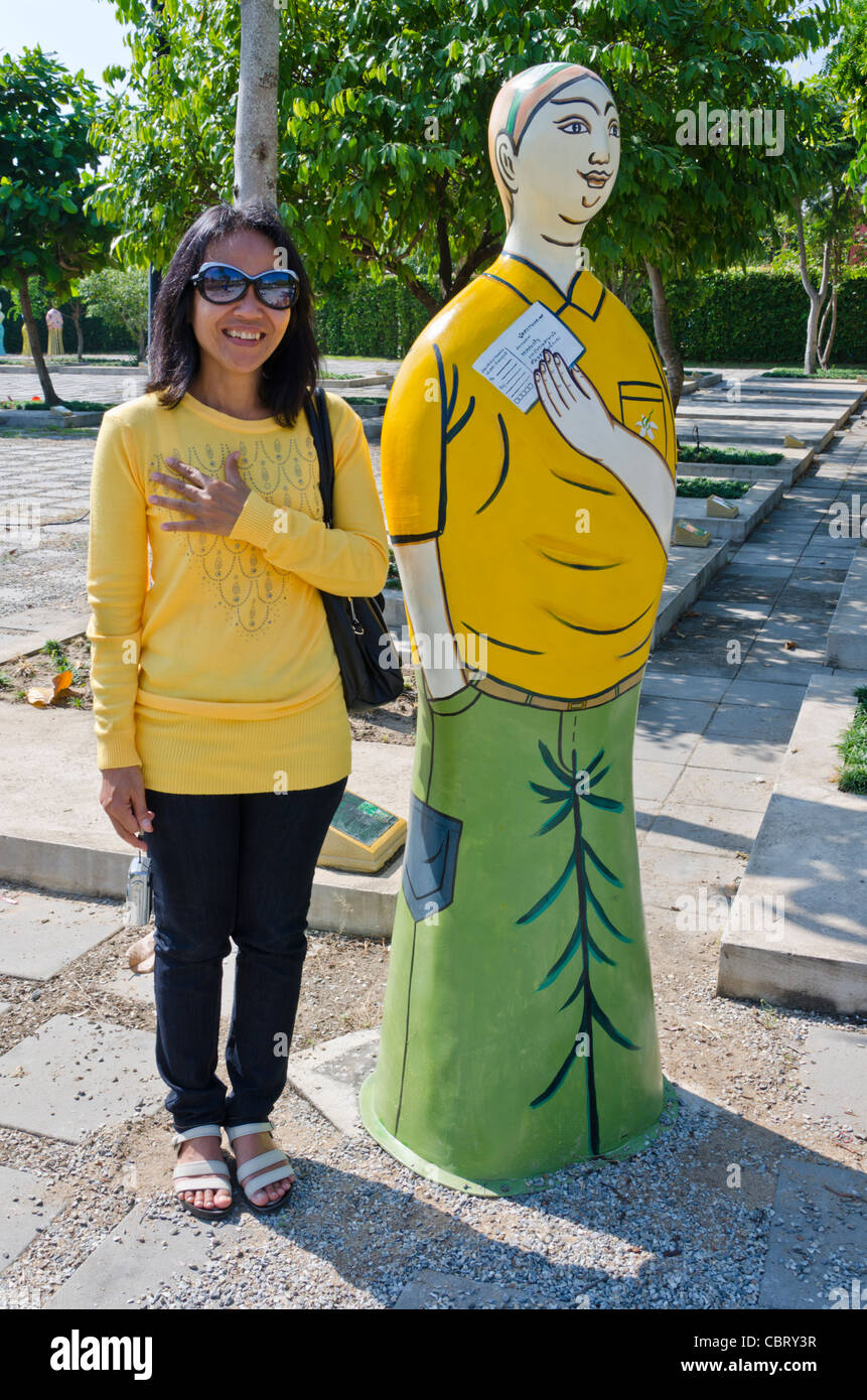 Woman in yellow top holds hand up to chest imitating statue next to her ...
