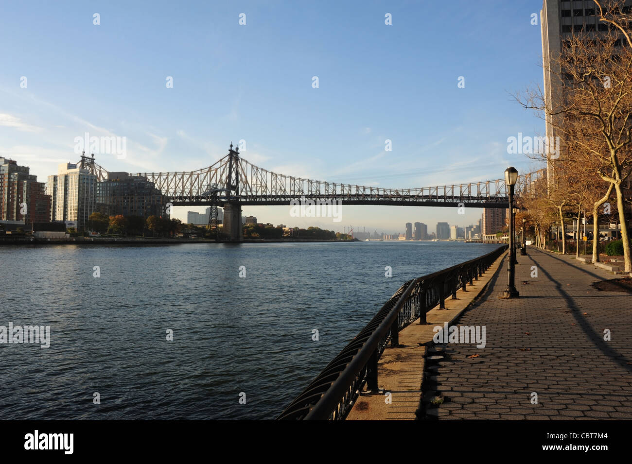 Blue sky autumn trees view East River Esplanade walkway, blue waters ...