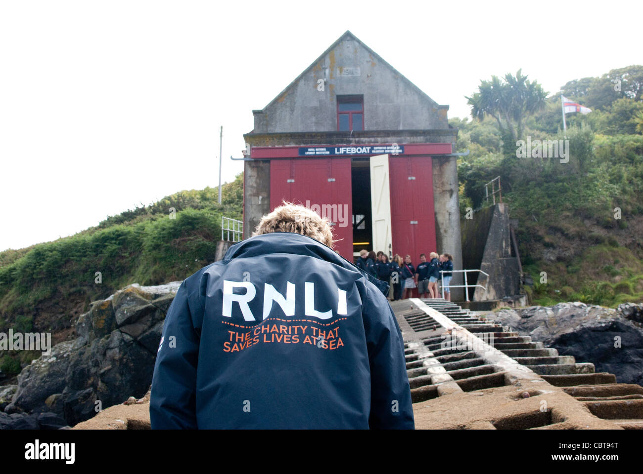 An RNLI member contemplates, with others in the background Stock Photo ...