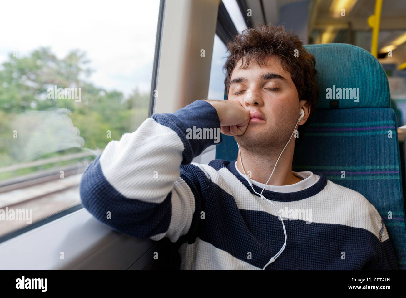 A young man is resting his eyes while he travels on a train Stock Photo ...
