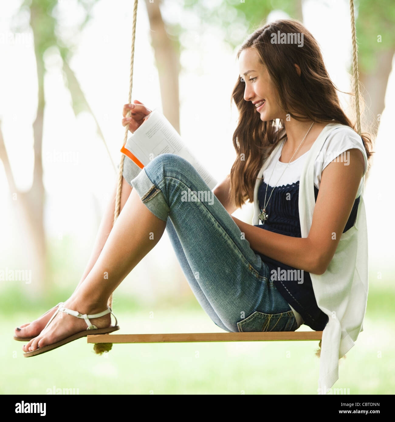 Caucasian girl reading book on swing Stock Photo - Alamy