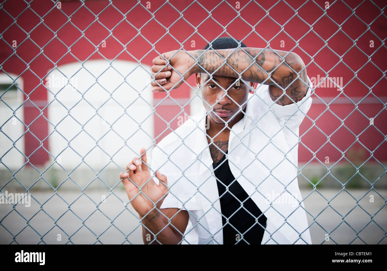 Black man leaning on chain link fence Stock Photo - Alamy