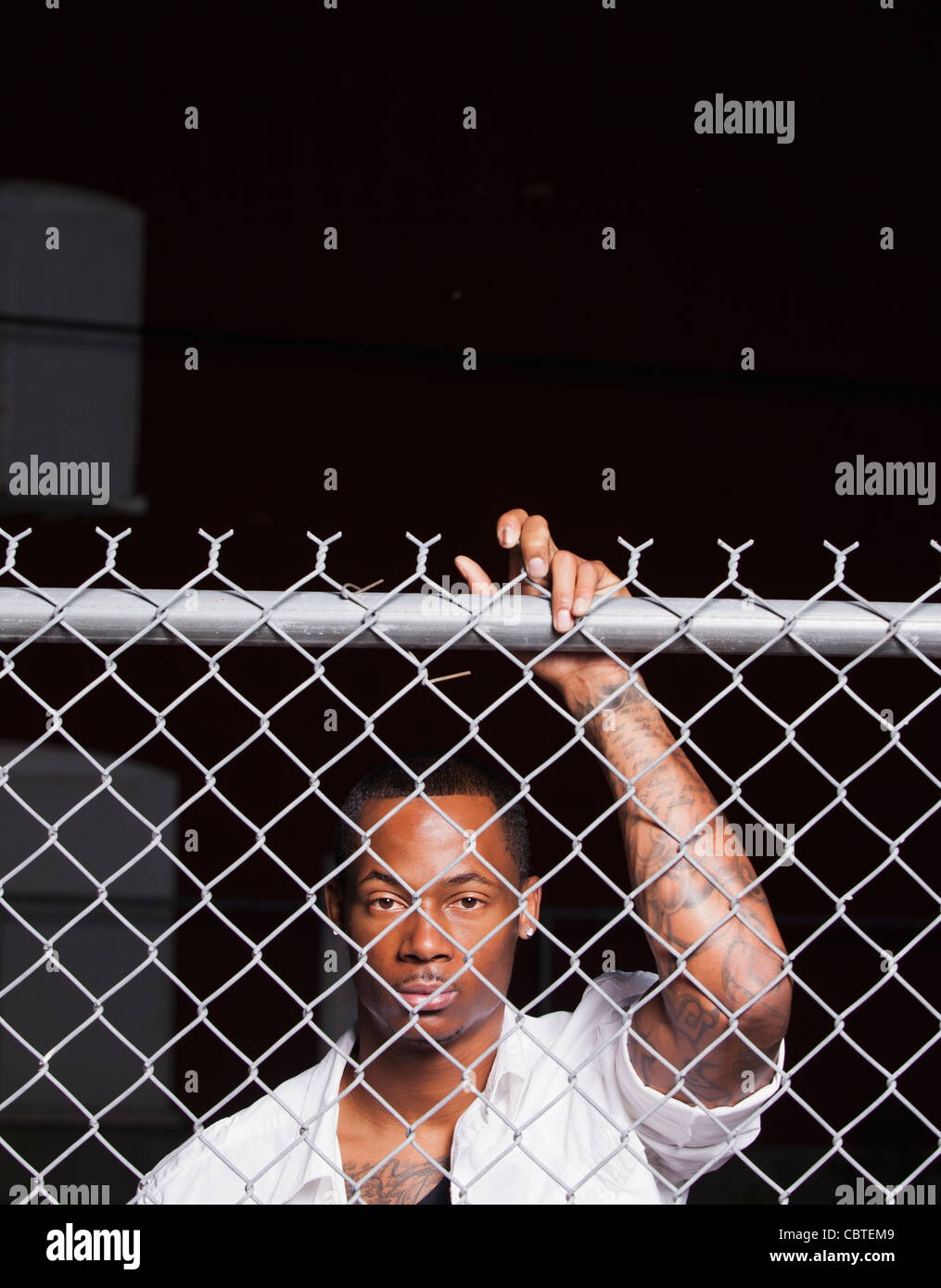 Black man leaning on chain link fence Stock Photo - Alamy