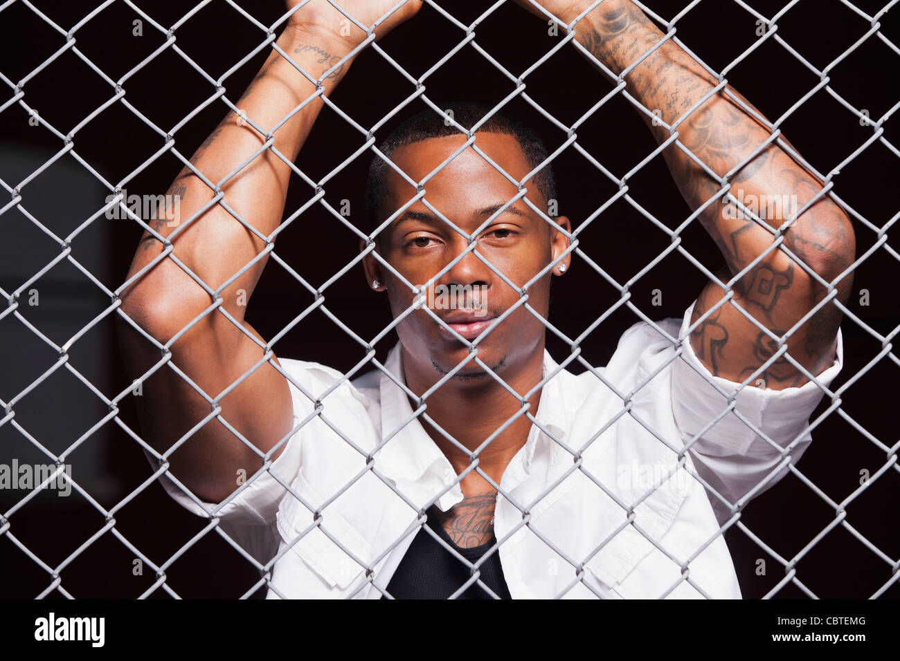 Black man leaning on chain link fence Stock Photo - Alamy