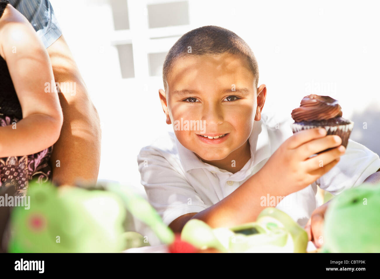 Mixed race boy eating chocolate cupcake Stock Photo - Alamy