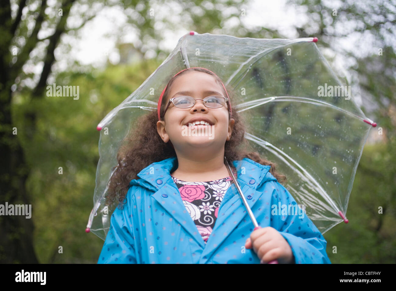 Hispanic girl standing in rain with umbrella Stock Photo - Alamy
