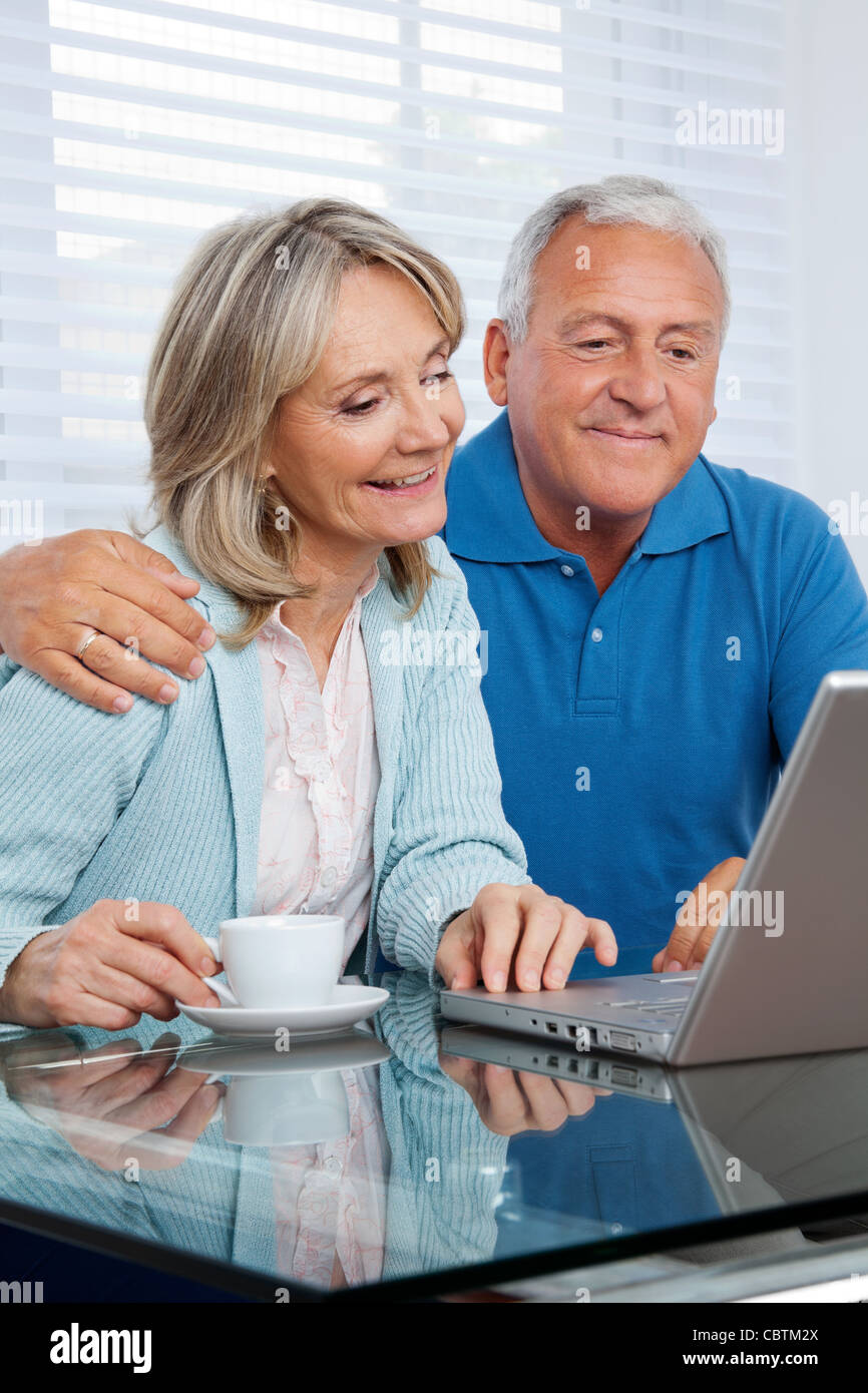 Happy couple browsing internet together on laptop Stock Photo - Alamy
