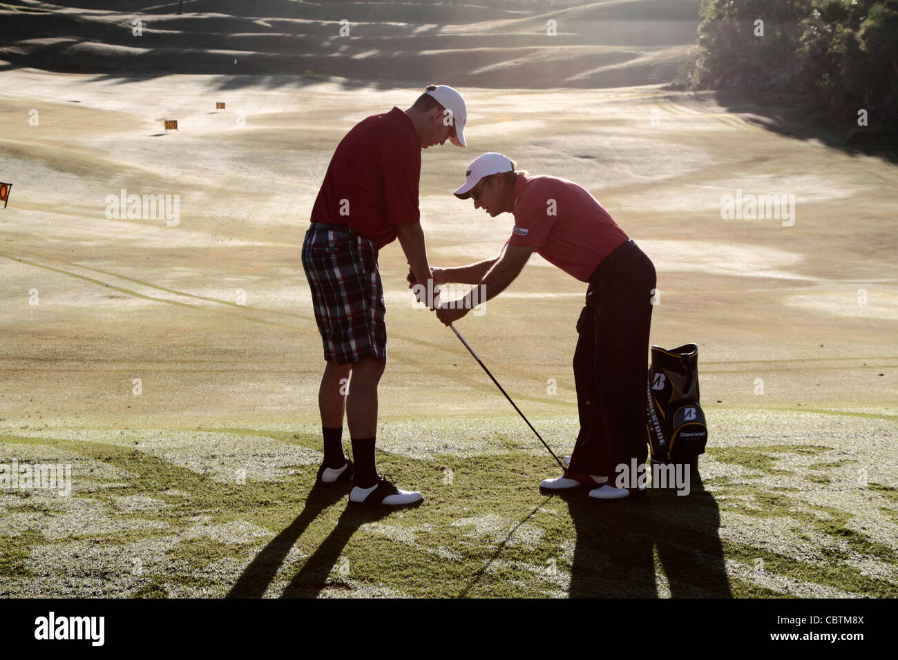 A golf pro helping a golfer with his grip on the driving range in the ...