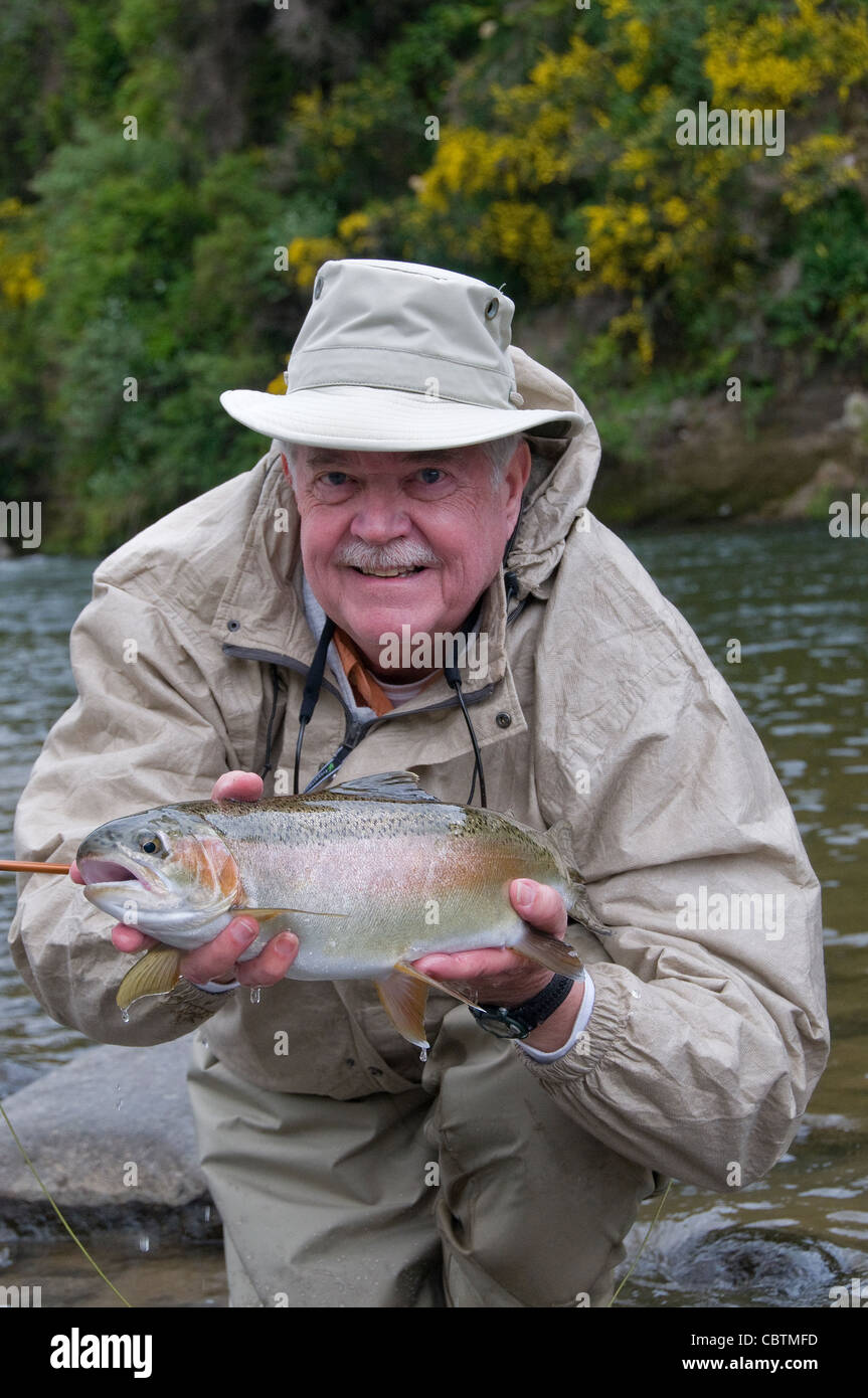 An angler admires his big trout caught in a small New Zealand river in ...