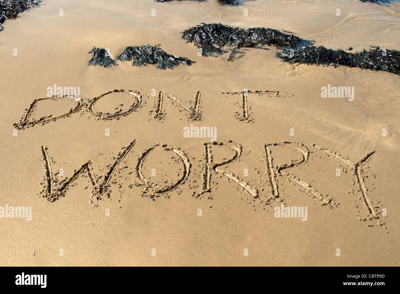 dont worry inscribed on the beach with waves in the background on a hot ...
