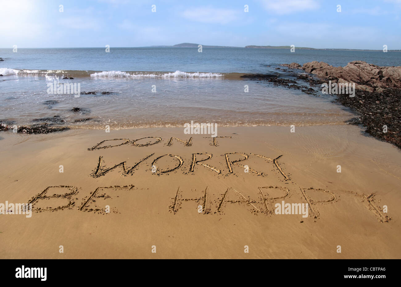 dont worry be happy inscribed on the beach with waves in the background ...