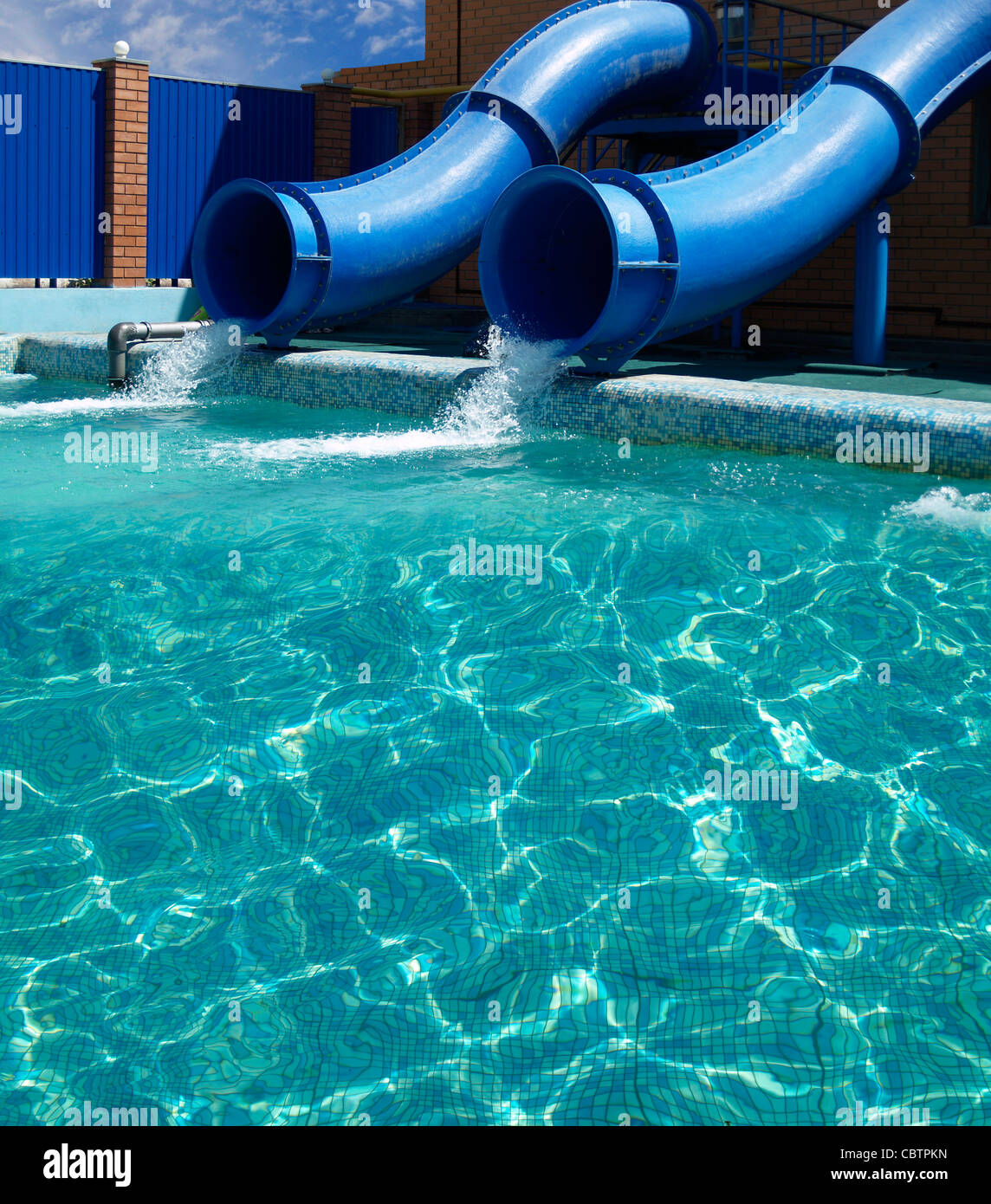 Swimming pool under the open sky with two pipes, blue water and ...