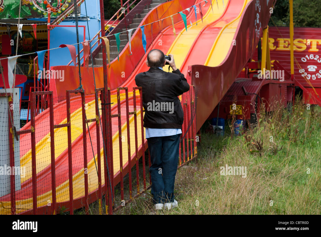 Man taking photograph at bottom of slide in fairground at Robin Hood ...