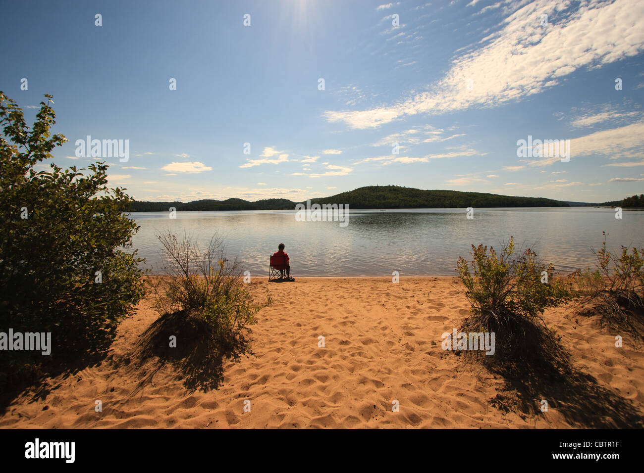 Sitting Alone on the Beach of a Calm Wilderness Lake Stock Photo - Alamy