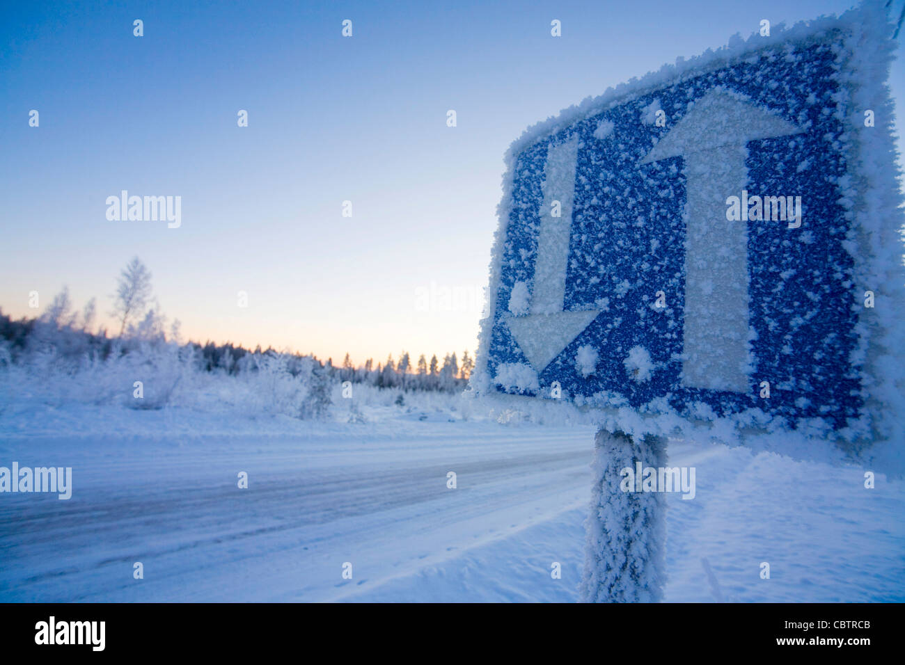 Frozen, two way traffic road sign on an iced up road in Arctic Finland ...