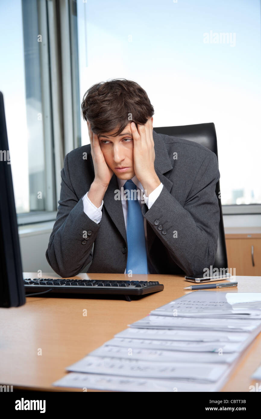 Stressed out businessman sitting at his desk in front of computer Stock ...