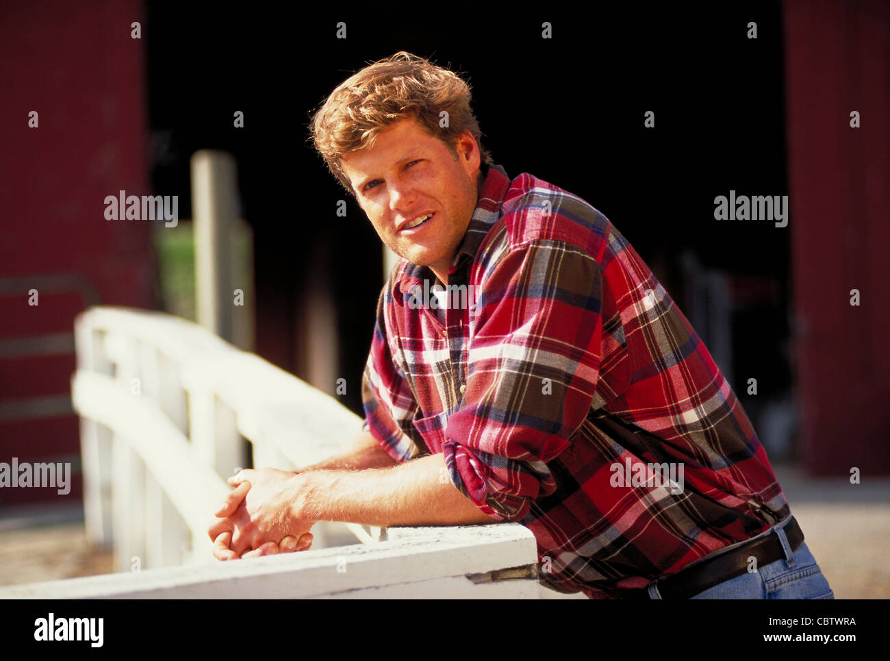 Cowboy at rest leaning on fence Stock Photo - Alamy