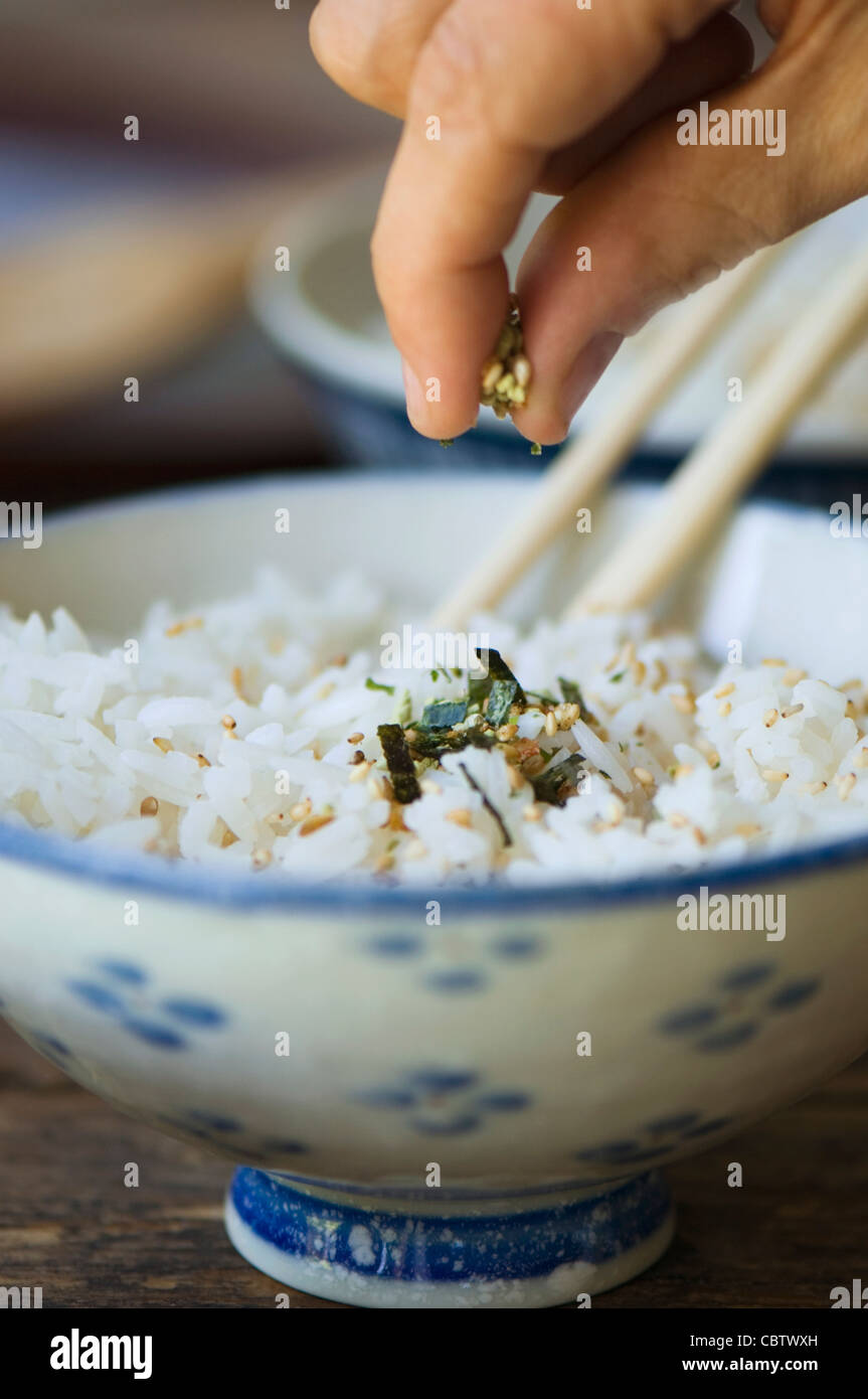 Hand putting seasoning on bowl of rice with chopsticks Stock Photo - Alamy
