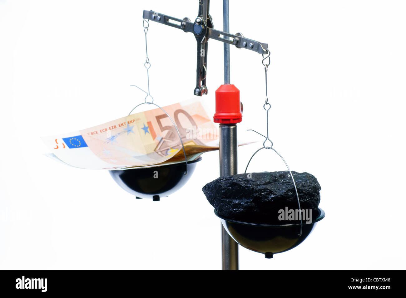 scale pan with money and coal Stock Photo - Alamy