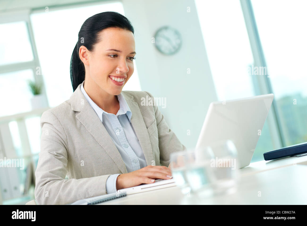 Portrait of pretty secretary looking at laptop screen while working ...