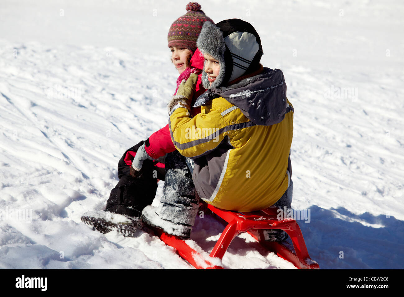 Two friends in winterwear sitting on sledge in park Stock Photo - Alamy