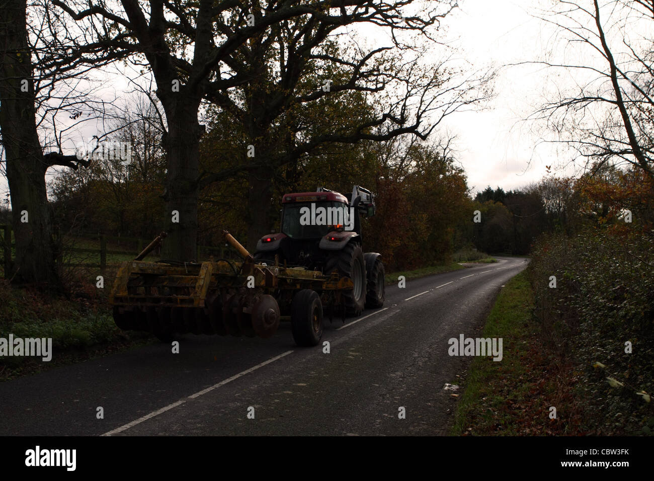 a tractor traveling along a rural road in Kent, England on a dull day ...