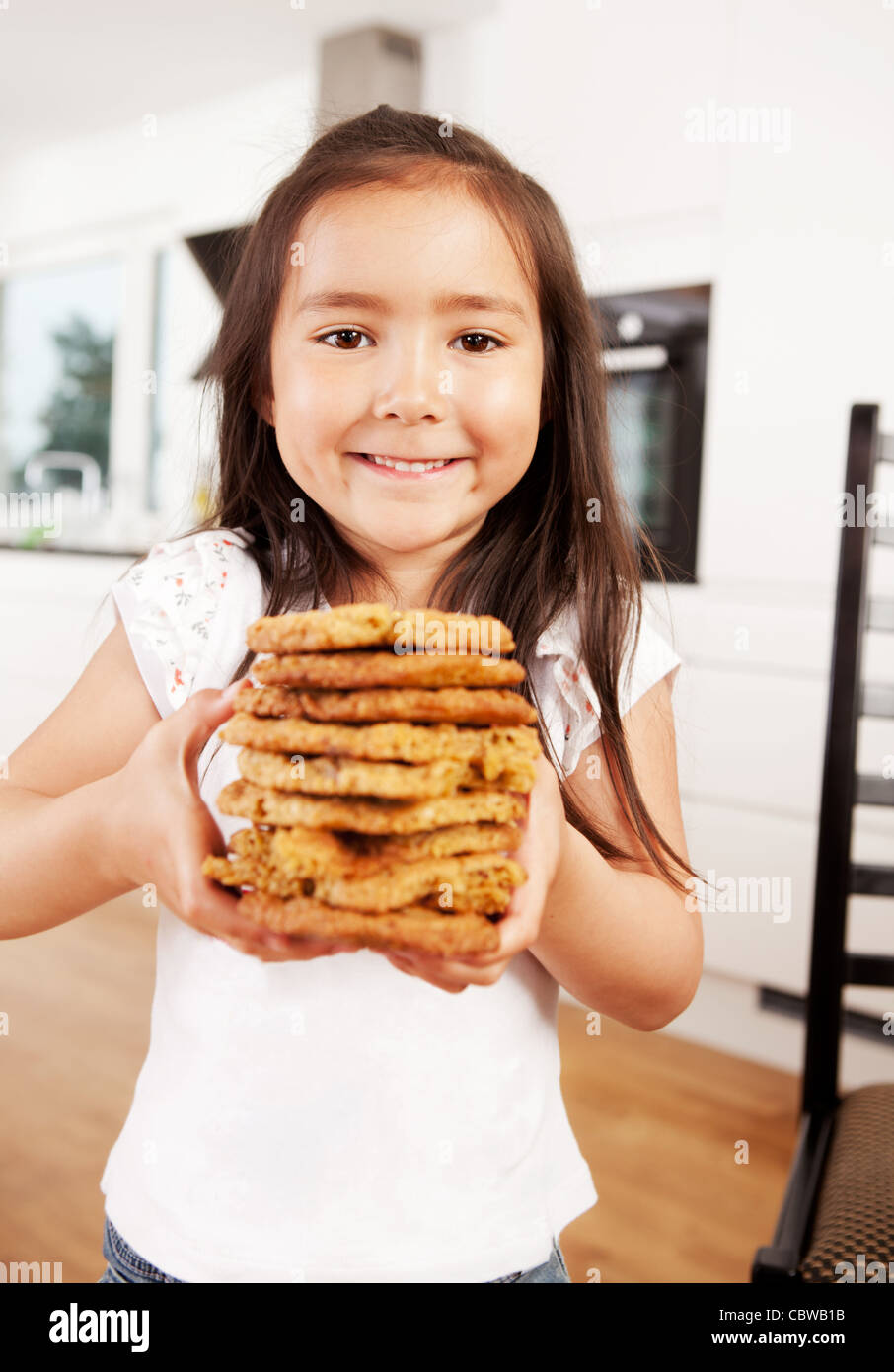 Happy cute girl looking at camera holding stack of freshly baked ...