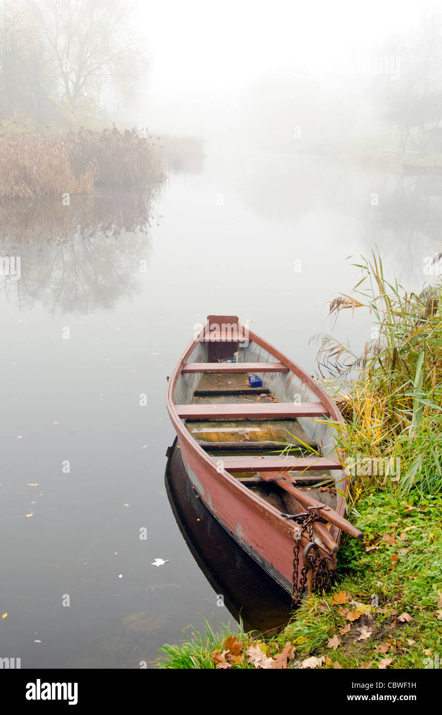Wooden rowing boat stands on coast of river sunken in dense fog Stock ...