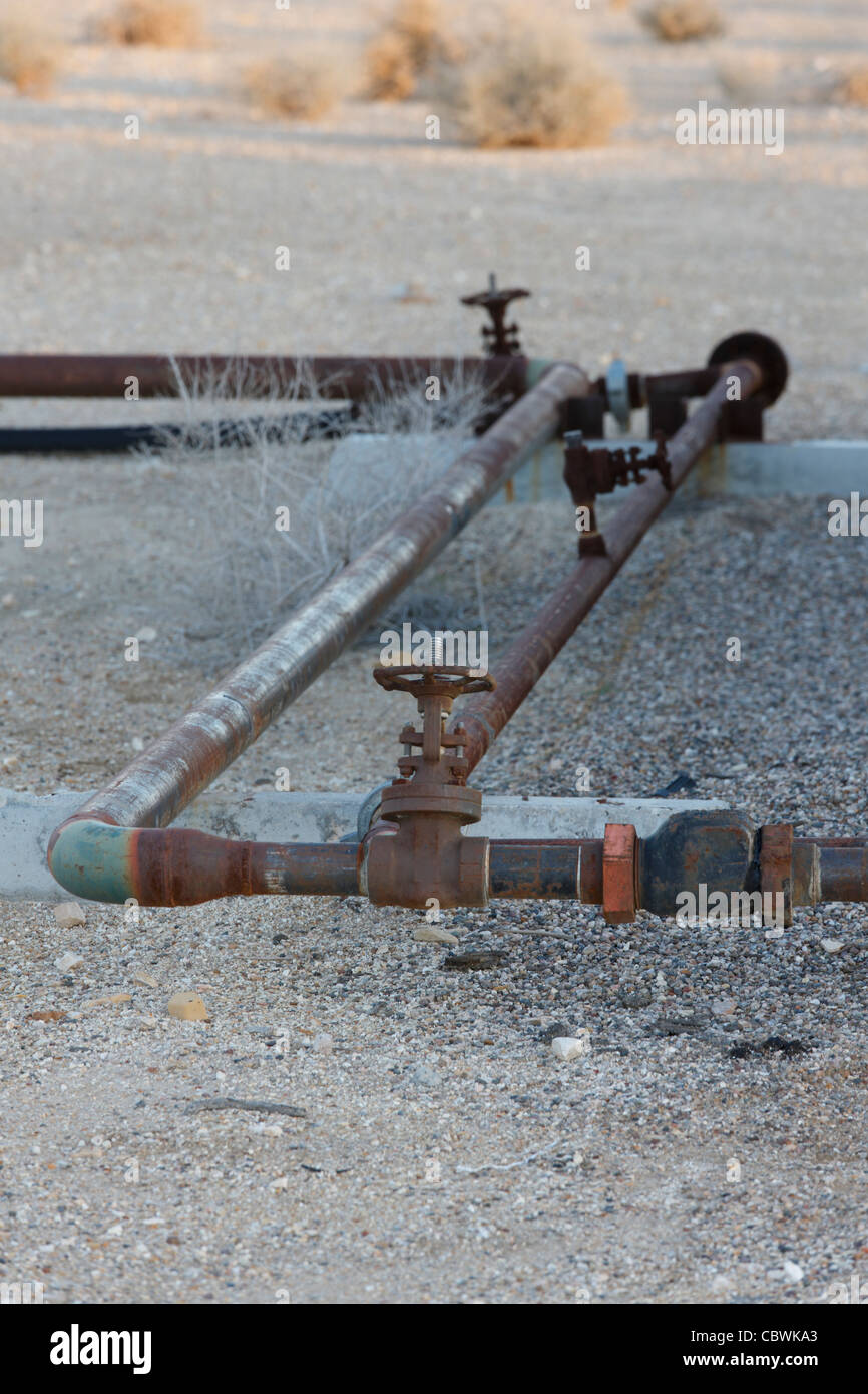 Close up of oil transfer pipes leading to and from and oil well head on ...
