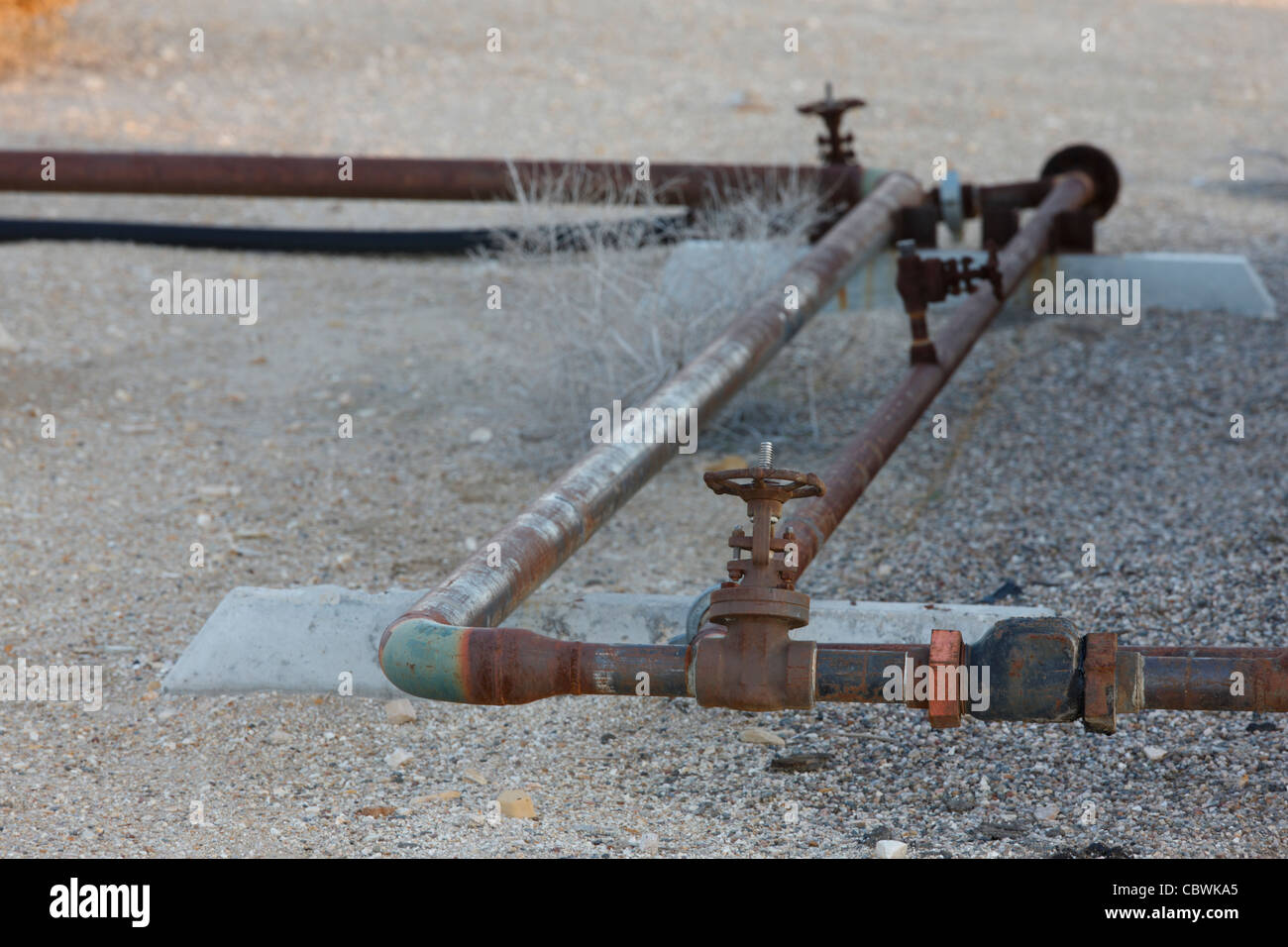 Close up of oil transfer pipes leading to and from and oil well head on ...
