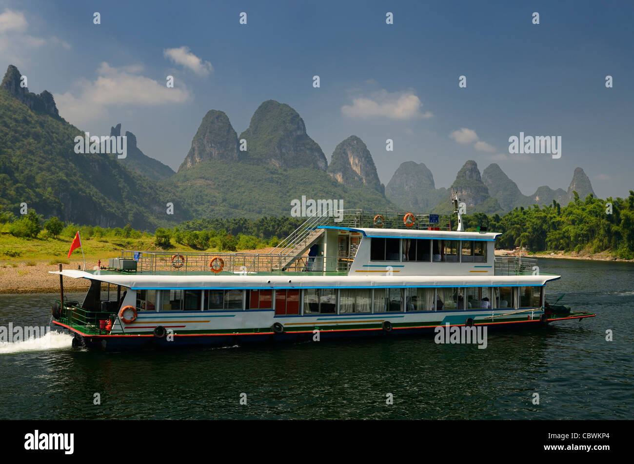 Chinese tour boat cruising down the Li river with bamboo forest and ...