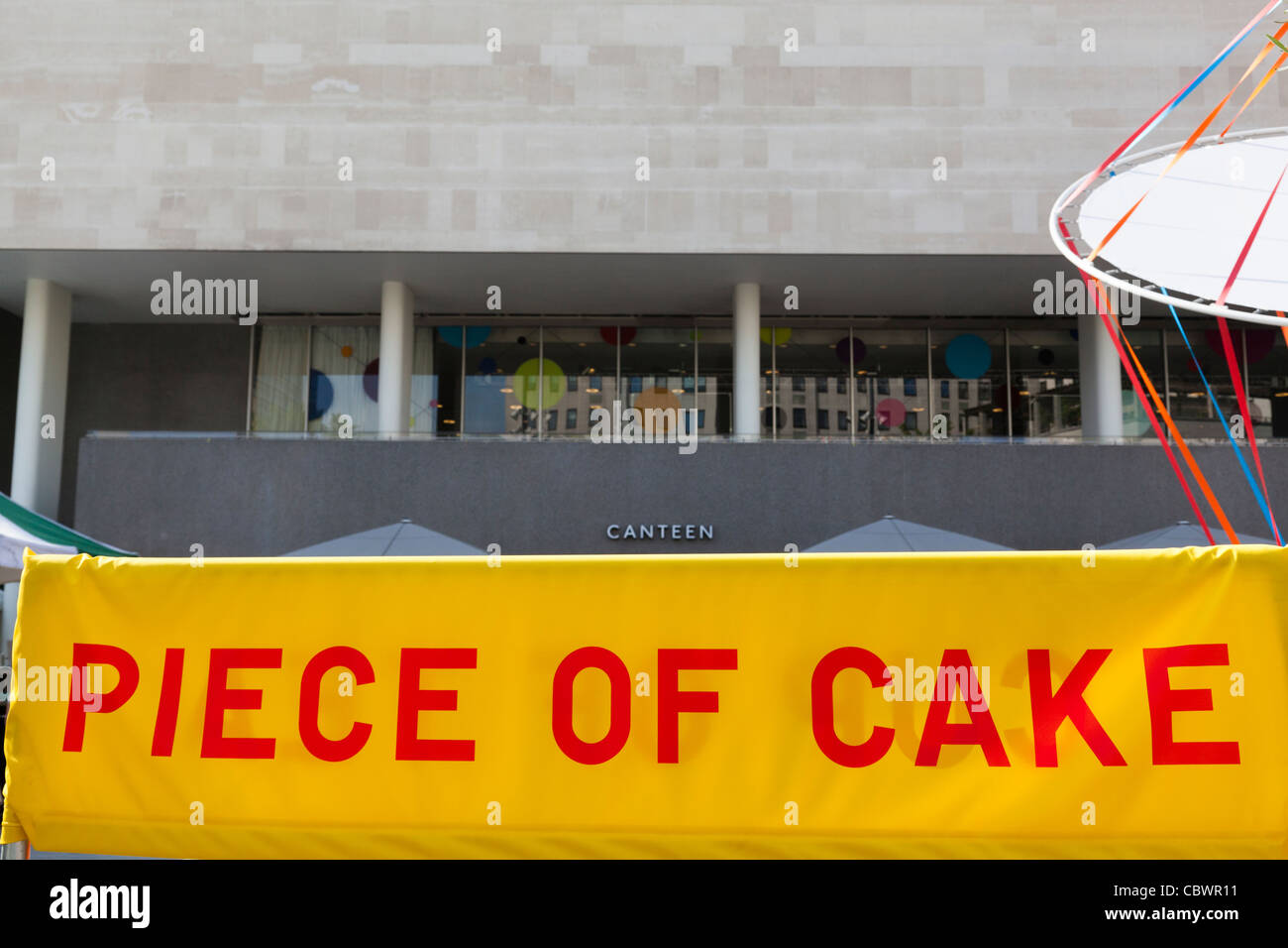 Large poster entitled 'piece of cake' juxtaposed with a canteen behind ...