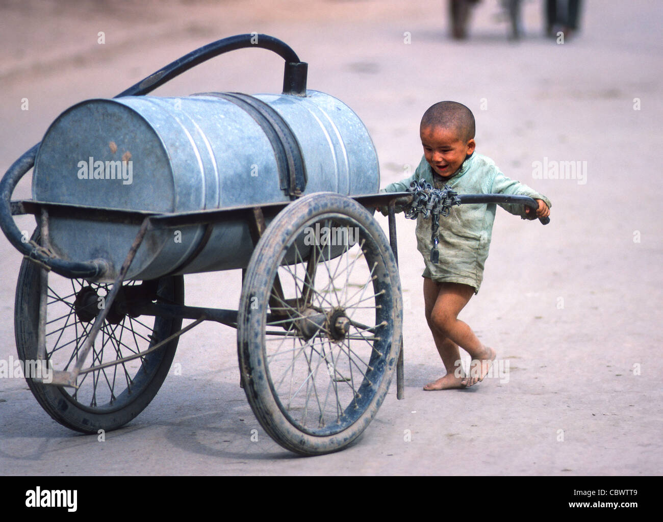 Small child pushing water cart Kashgar Western Xinjiang China Stock ...