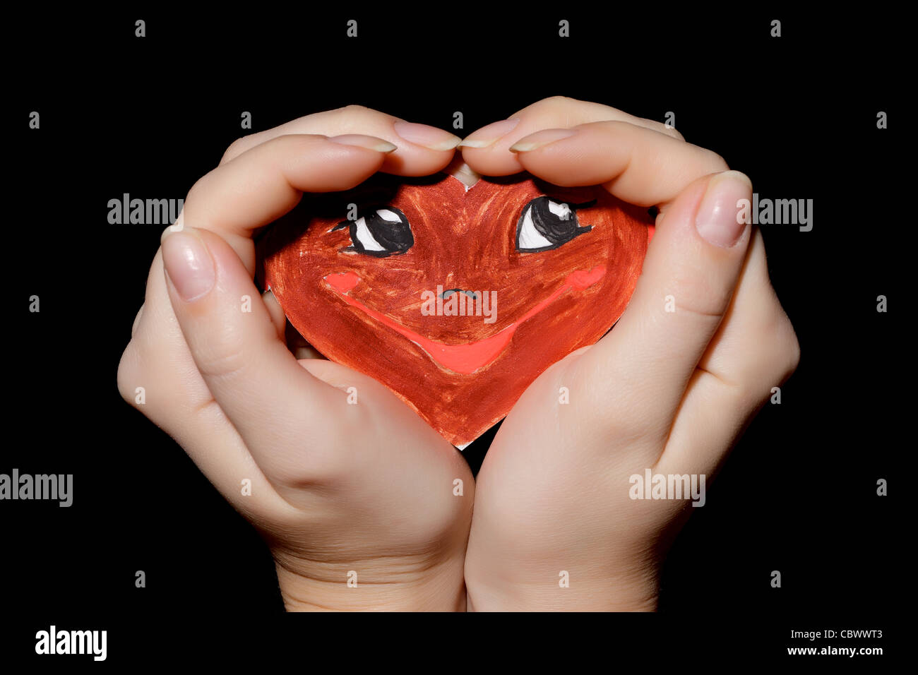 Smiling heart in hands on black background Stock Photo - Alamy