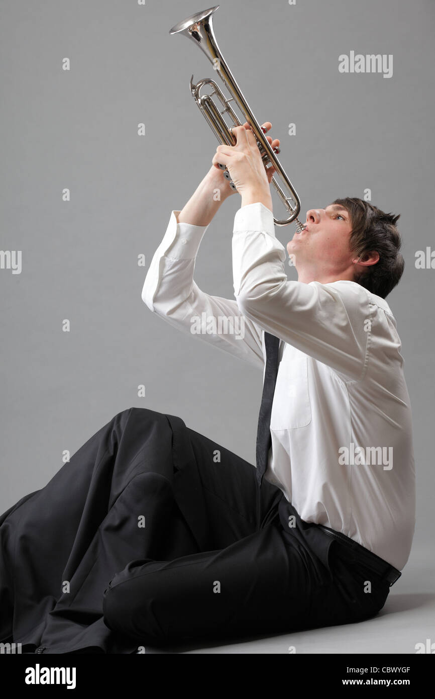 Portrait of a young jazz man playing his Trumpet grey background Stock ...