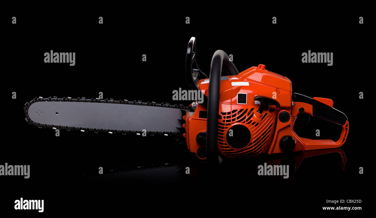 New red chainsaw isolated on black Stock Photo - Alamy