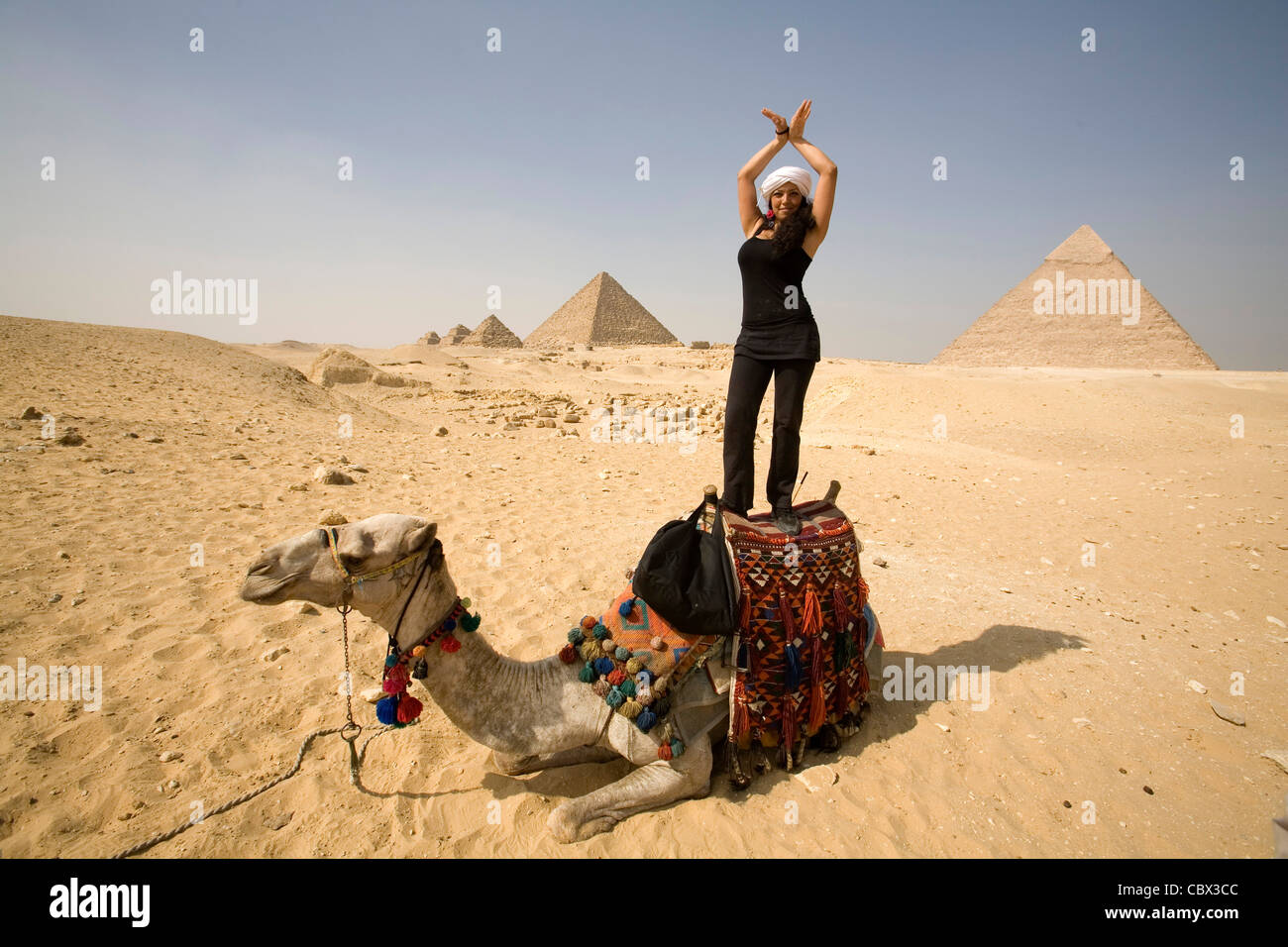 Woman standing on top of a camel in front the pyramids, Giza il Cairo ...