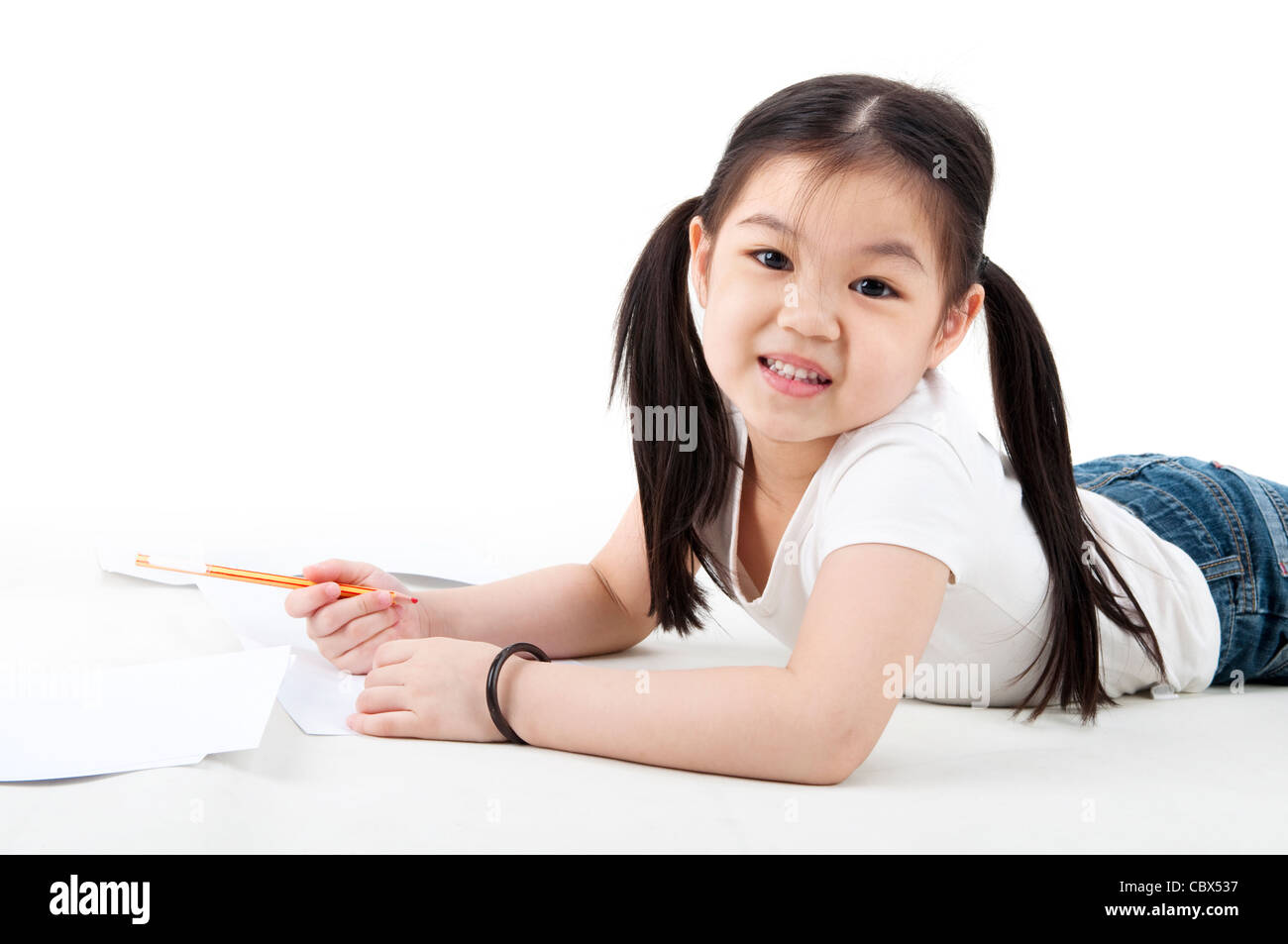 Little Asian girl drawing, lying on floor Stock Photo - Alamy