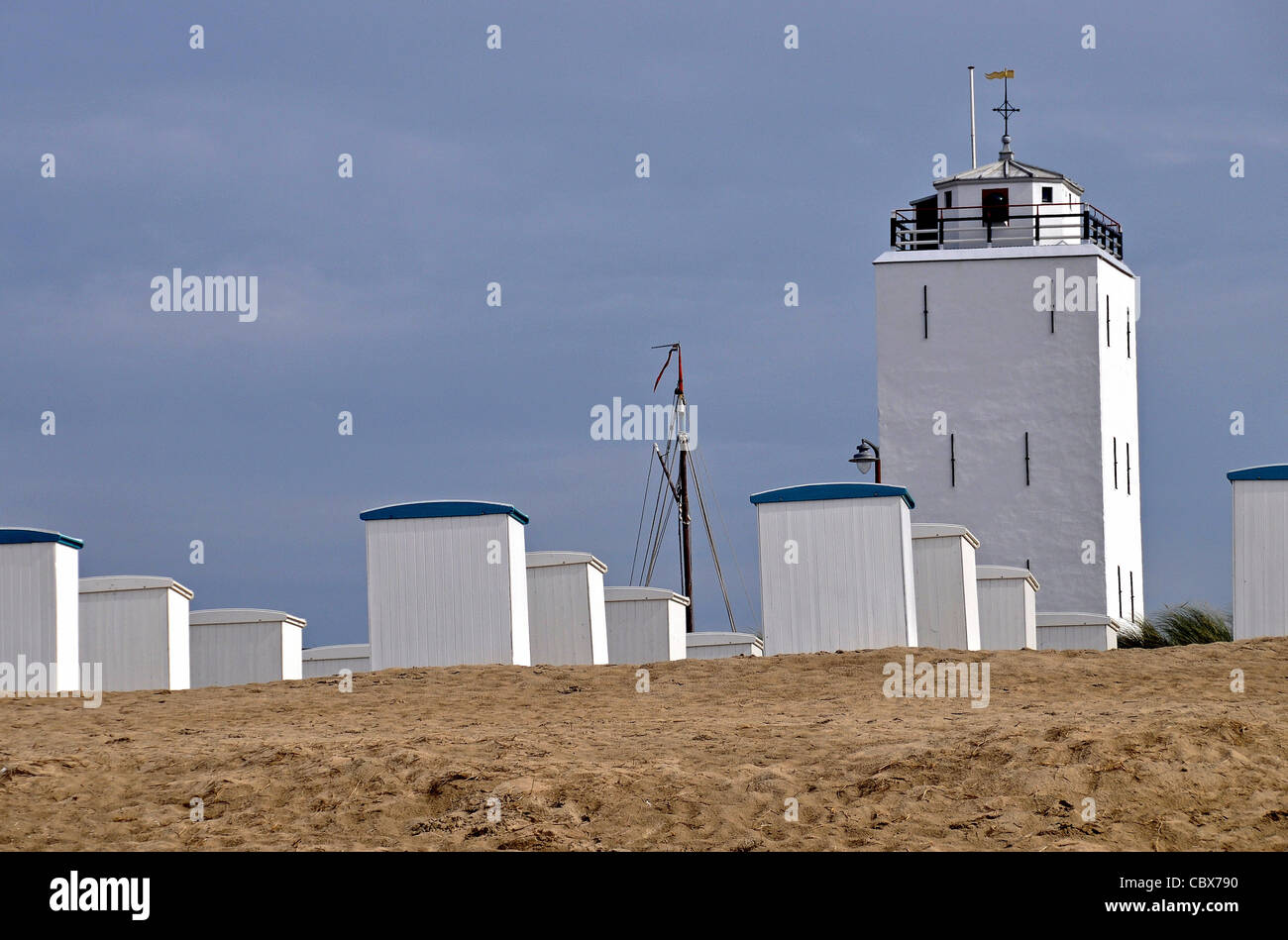 Historic white lighthouse and white wooden beach huts on the beach of ...