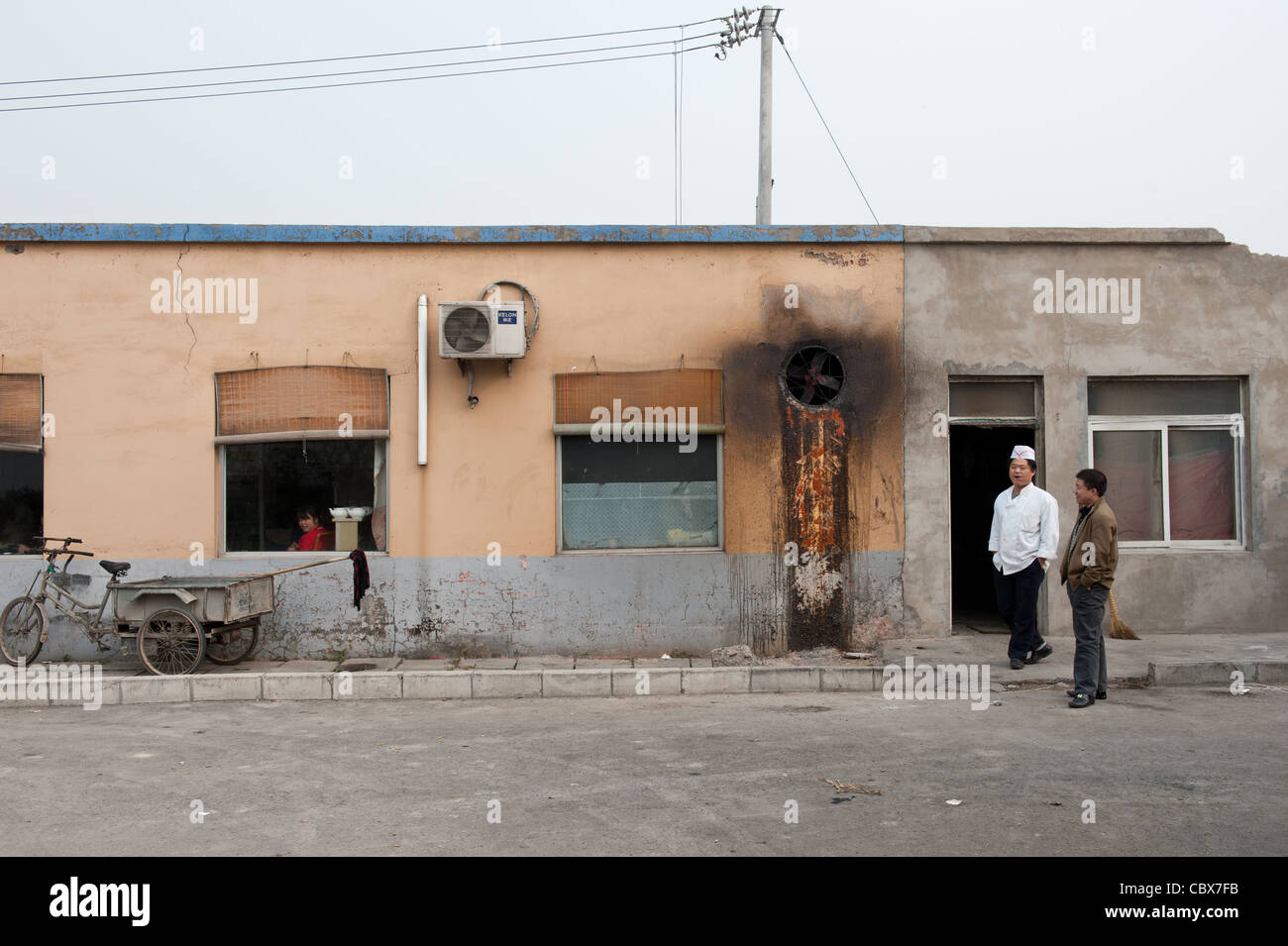 LaiGuangYing, Beijing. Cook having a rest in front of his kitchen Stock ...
